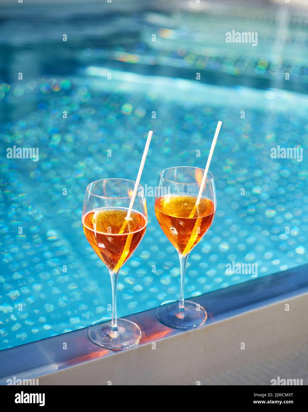 Close up of glasses with summer cocktails standing under scorching sun ...