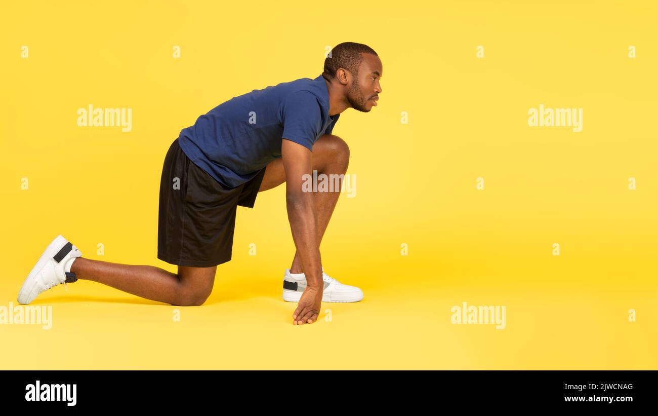 African Runner Guy Standing In Crouch Start Position, Yellow Background ...