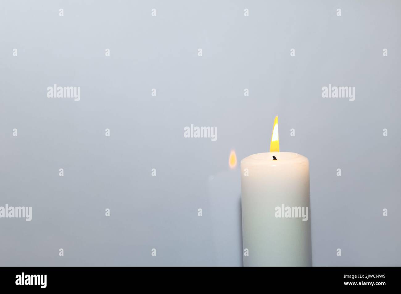 White candle at white background . Burning wax candle Stock Photo - Alamy