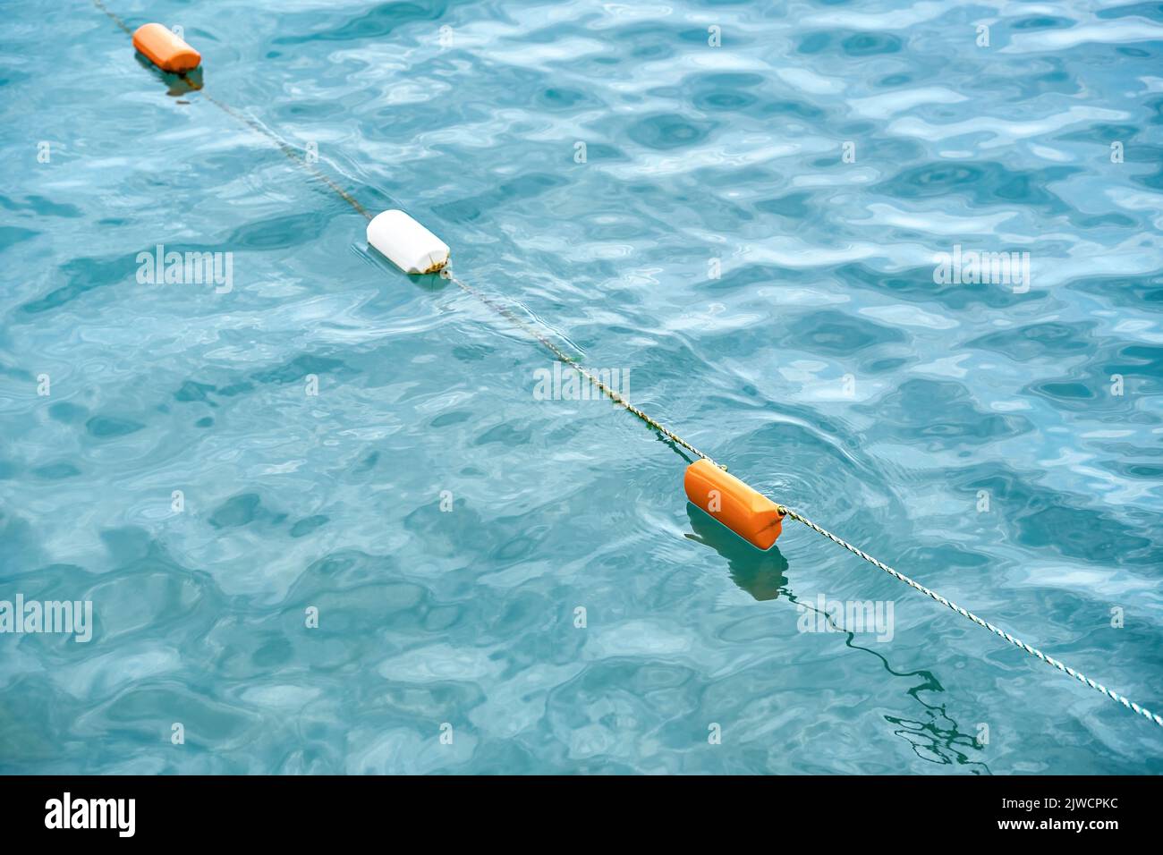 Installed bright red and white buoys waving on blue water surface ...