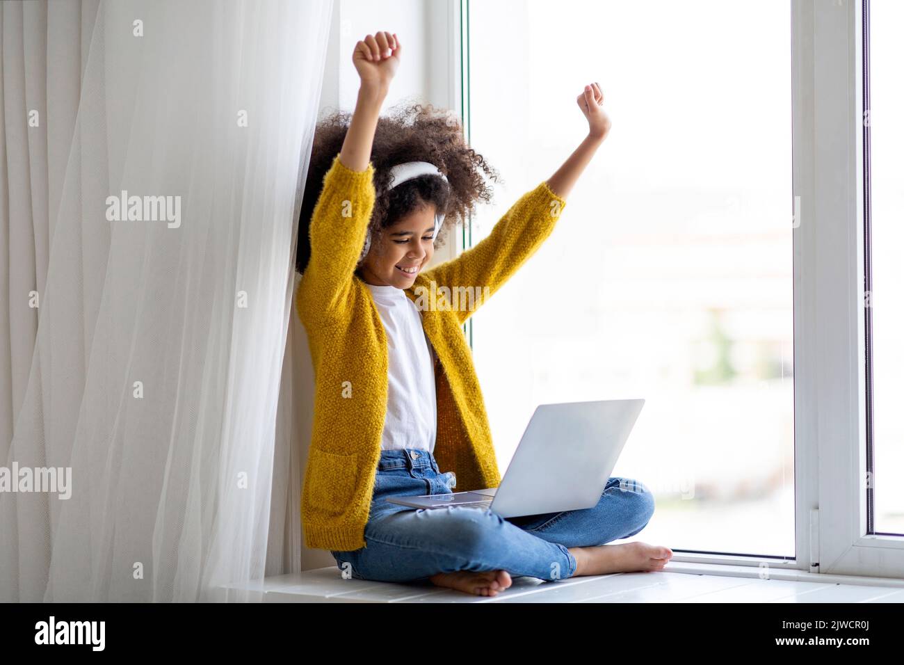 Emotional little black girl with wireless headset using laptop Stock ...