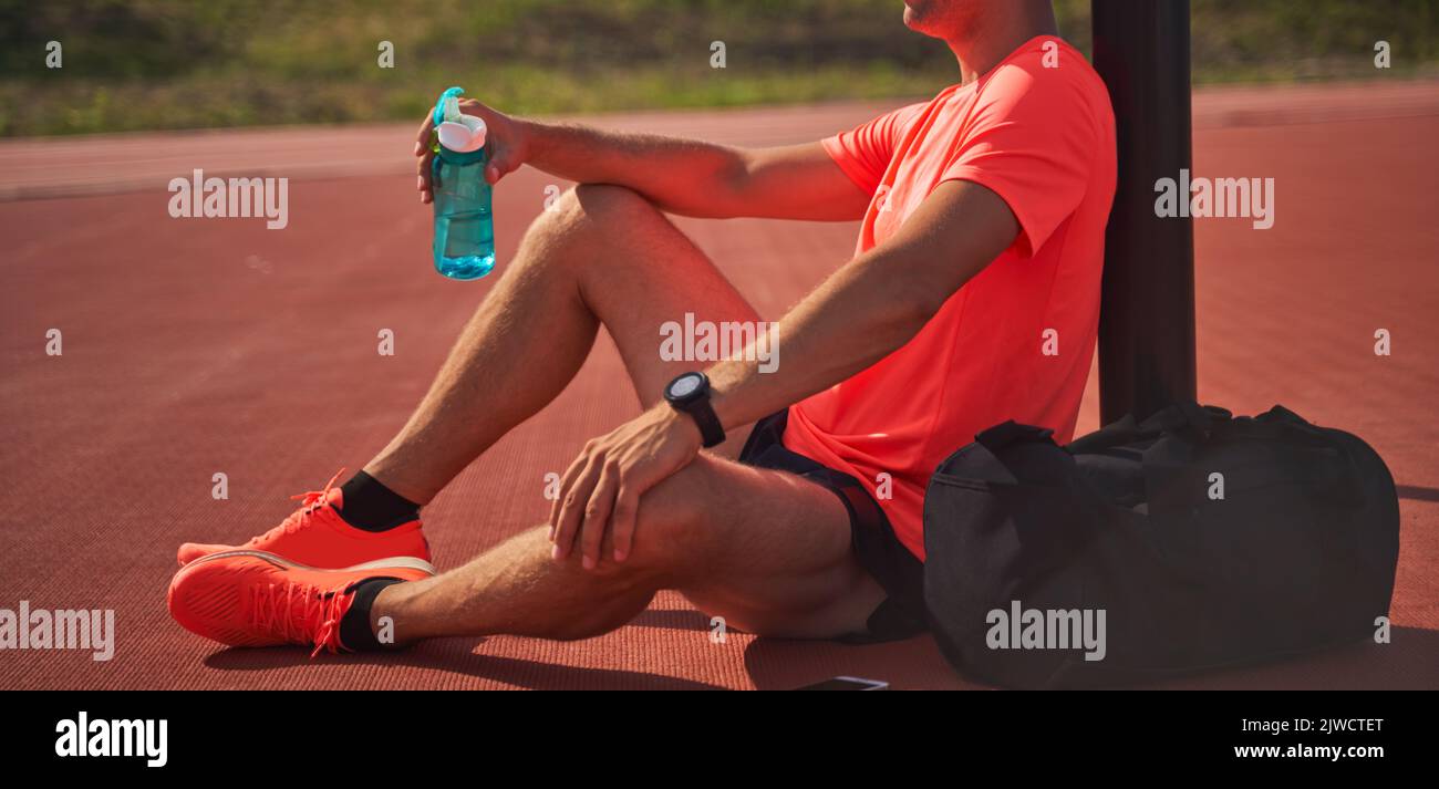 Sport man in sportive clothes relaxing after workout at the stadium ...