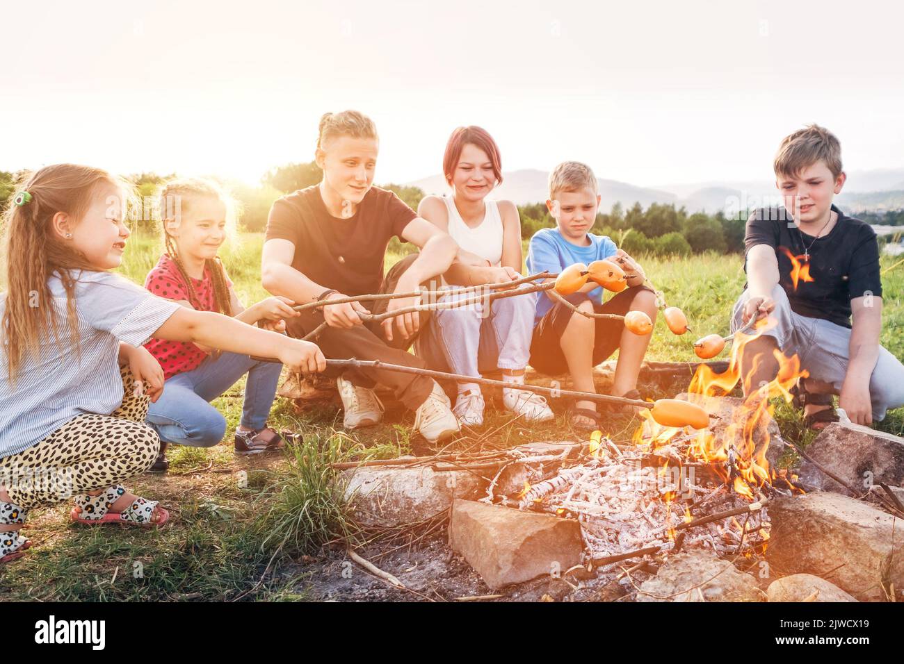 Six kids group Boys and girls cheerfully laughed and roasted sausages ...