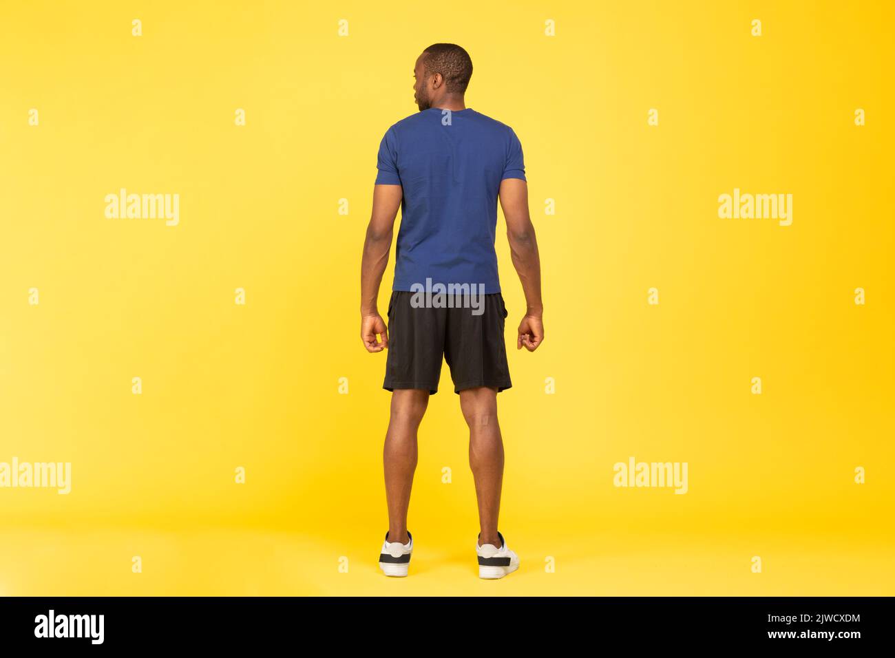 Rear View Of Sporty Black Man Standing Over Yellow Background Stock ...