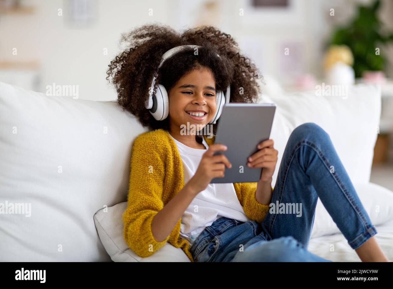 Happy kid sitting on couch, using digital tablet and headset Stock ...
