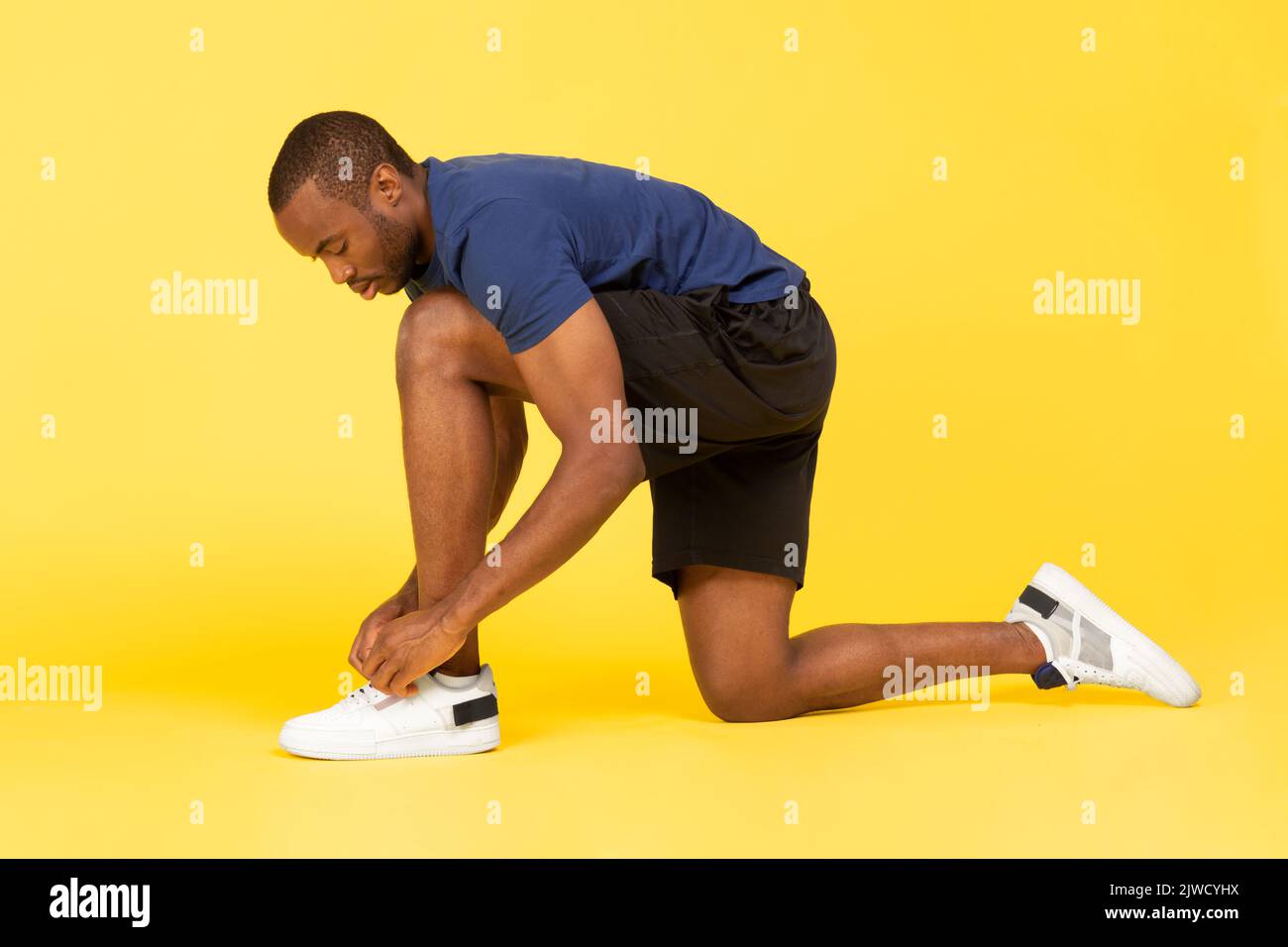 Black Male Runner Lacing Shoes Preparing For Race, Yellow Background ...