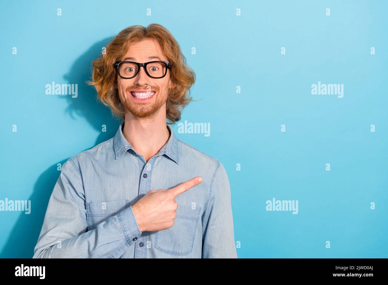 Photo of cheerful funky man wear denim shirt spectacles pointing empty ...