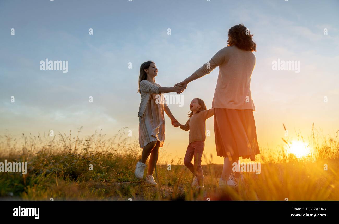 Happy family at sunset. Mother and children are having fun and enjoying ...