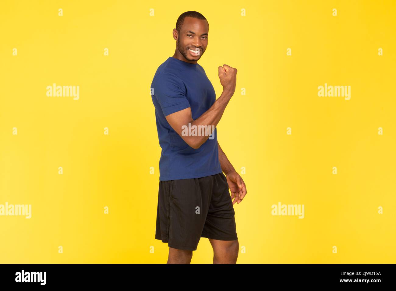 Sporty African American Man Showing Biceps Muscles Over Yellow ...