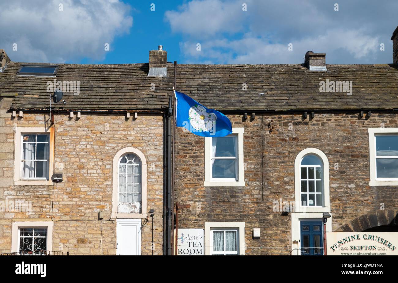White rose of Yorkshire flag flying close to a row of stone terraced ...