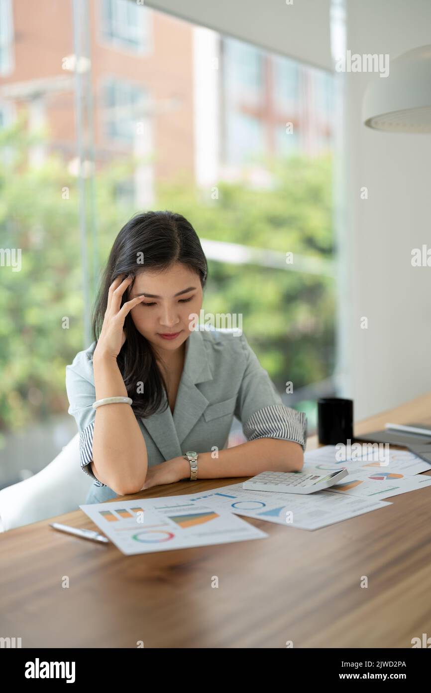 Thoughtful asian woman managing budget and finances using calculator in ...