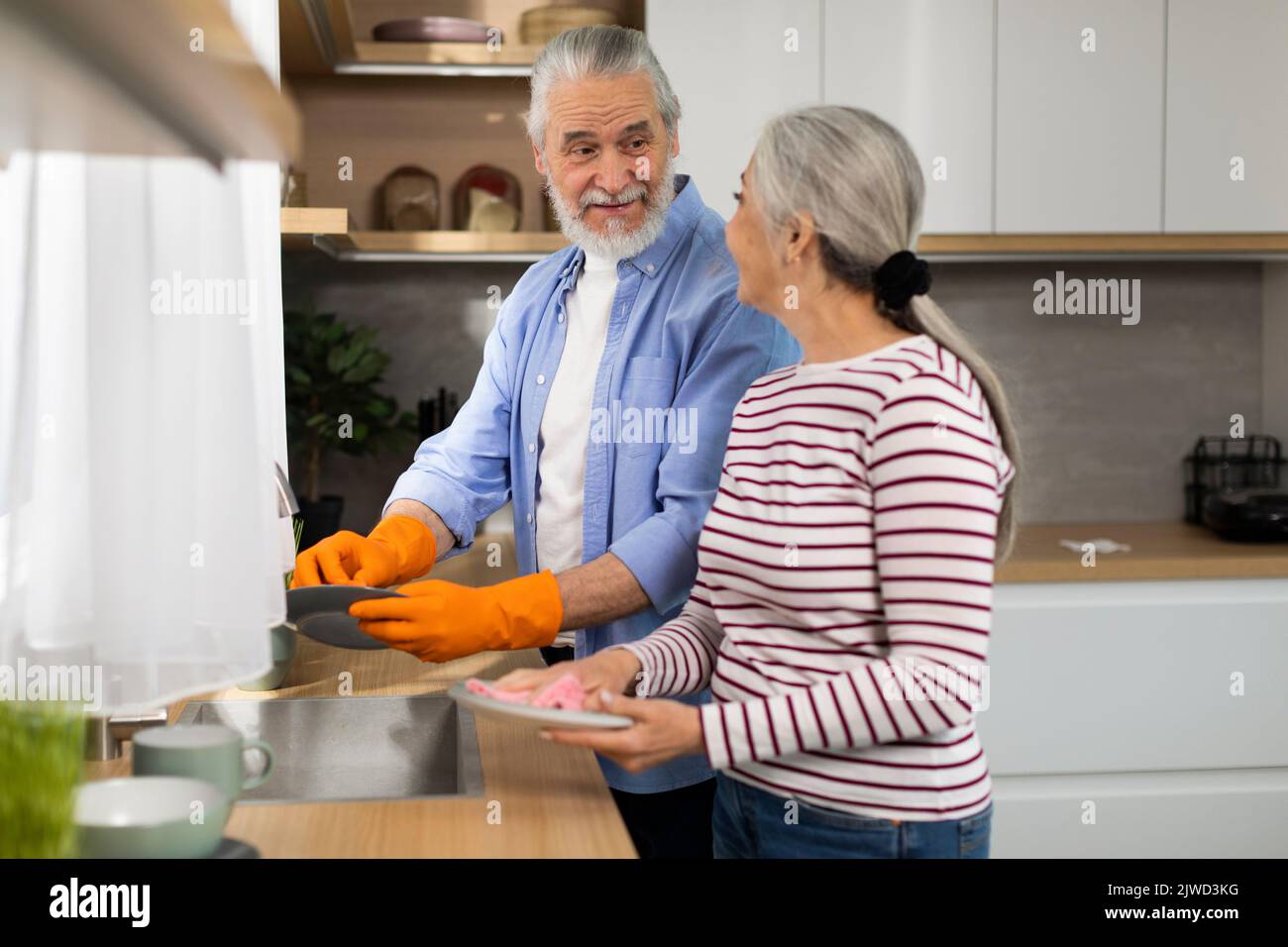 Helping Hand. Happy Senior Man Helping Wife With Dishes In Kitchen ...