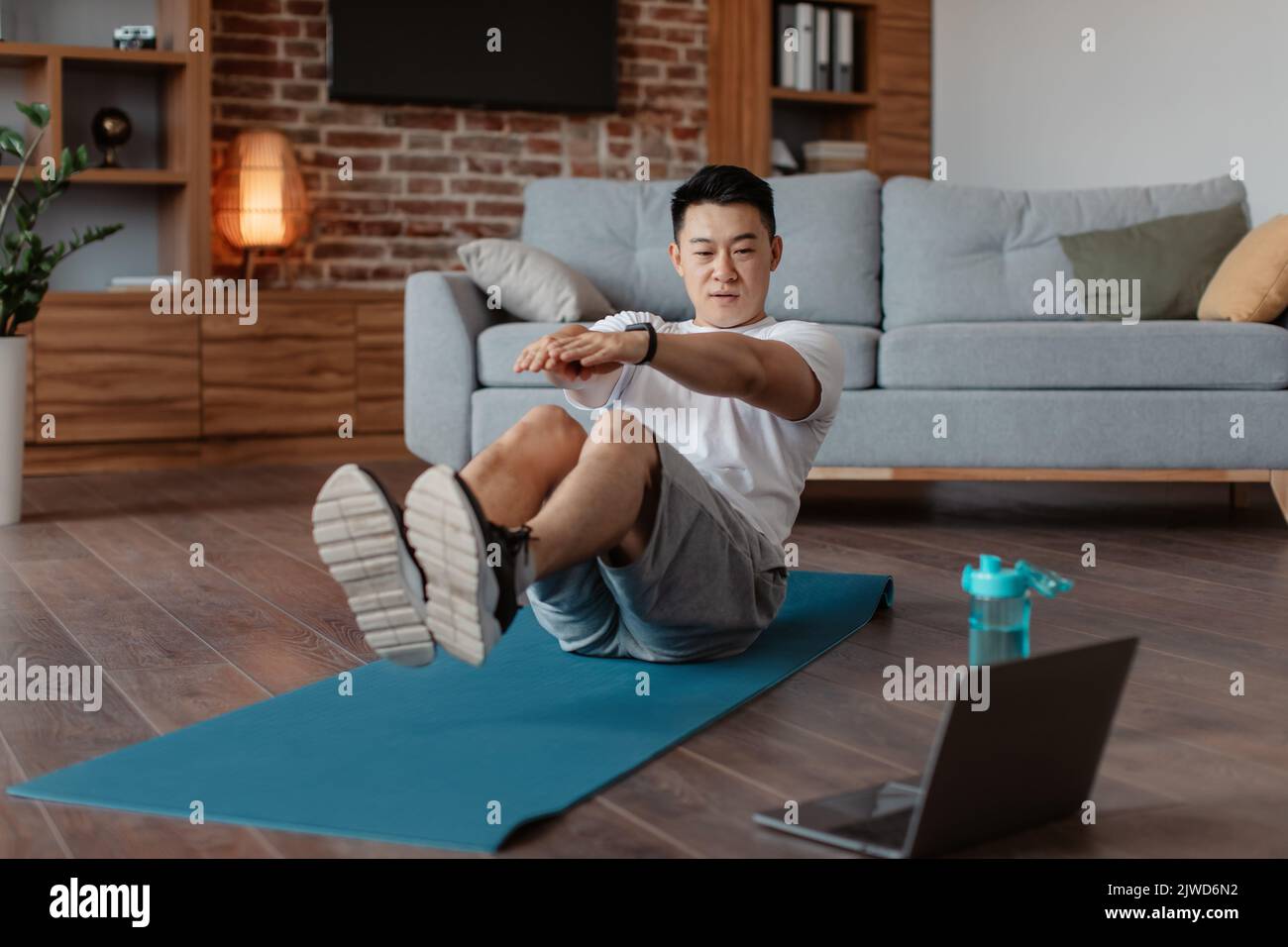 Mature korean man doing exercises for abs on mat on floor in living ...