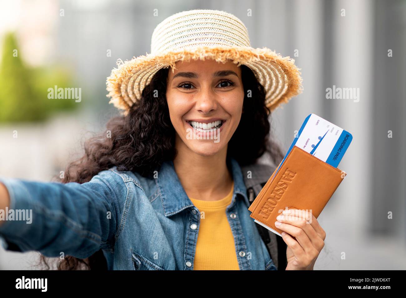Excited middle eastern woman taking selfie, showing flight tickets ...