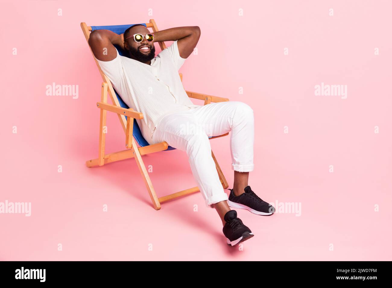 Photo of adorable funny guy dressed white shirt sitting deck chair arms ...