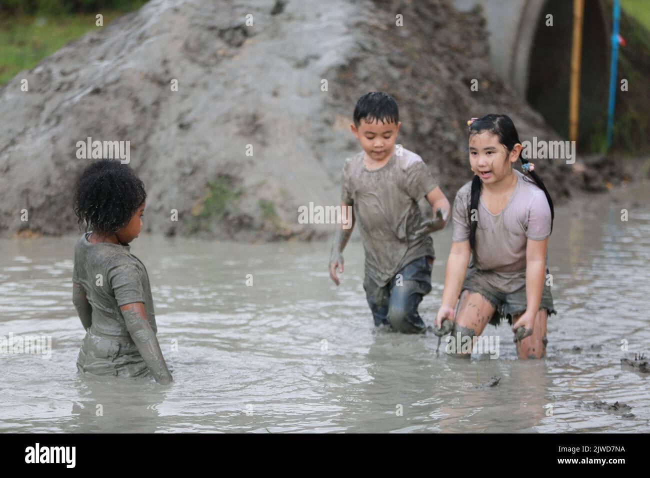 Group of kids playing on muck in the raining day Stock Photo - Alamy