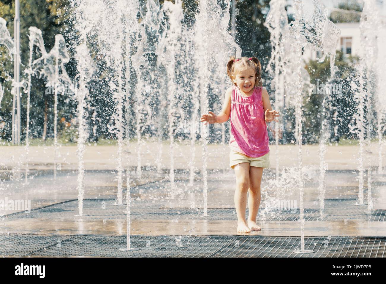 Happy kid playing in a fountain with water Stock Photo - Alamy