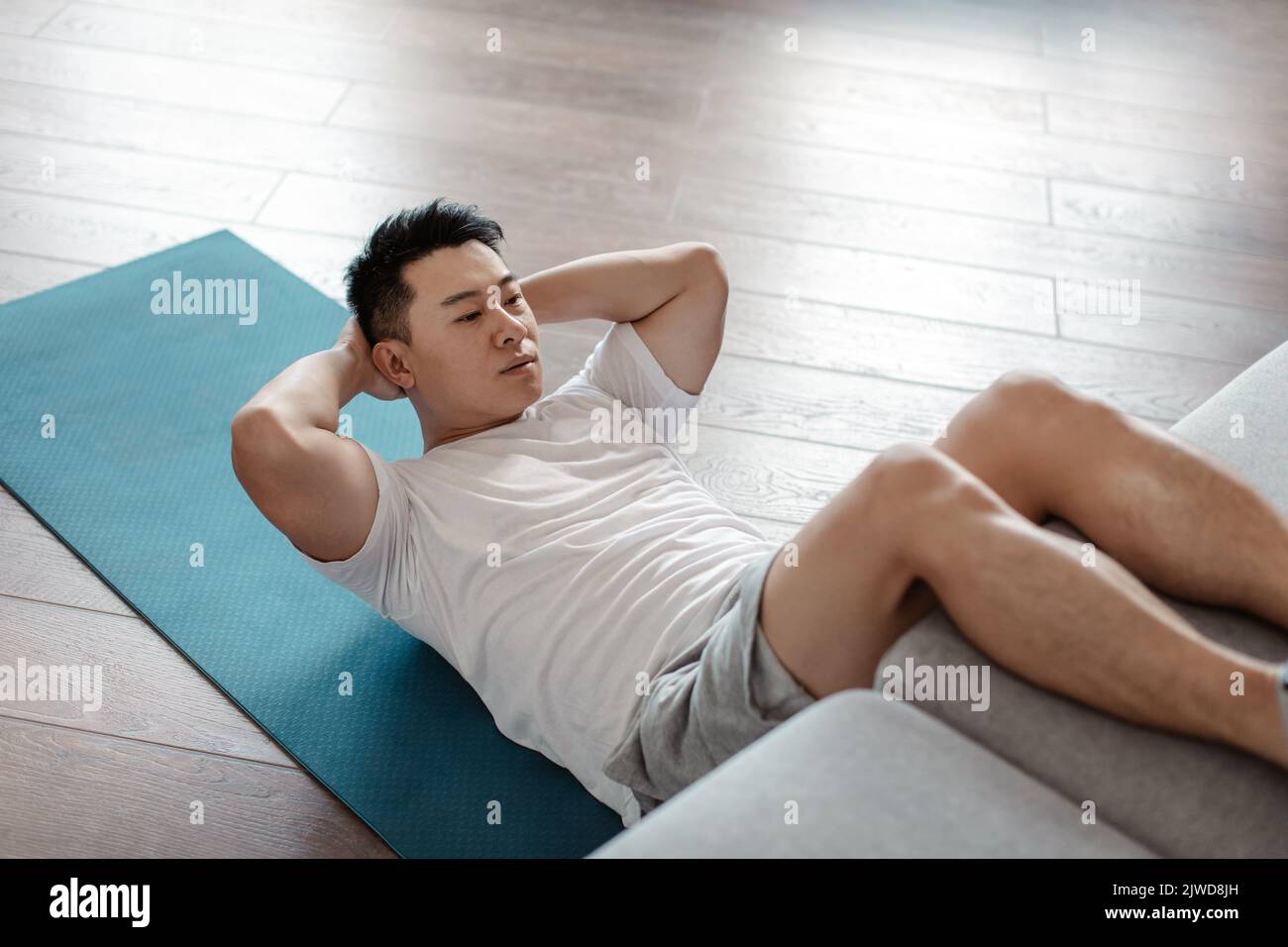 Athletic korean mature man exercising abs muscles on yoga mat, putting ...