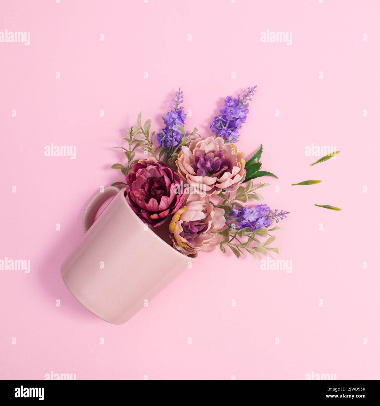 Pastel pink ceramic cup with spring flowers in it. Flat lay creative ...