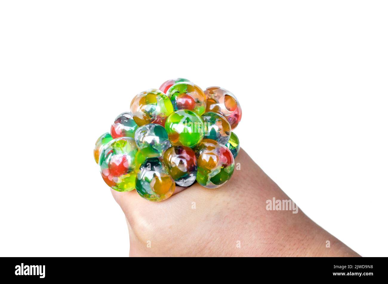 Hand of a girl squeezing a colorful stress ball on white background ...