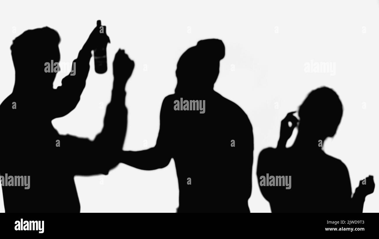 shadow of man with bottle of beer near silhouettes of dancing friends ...