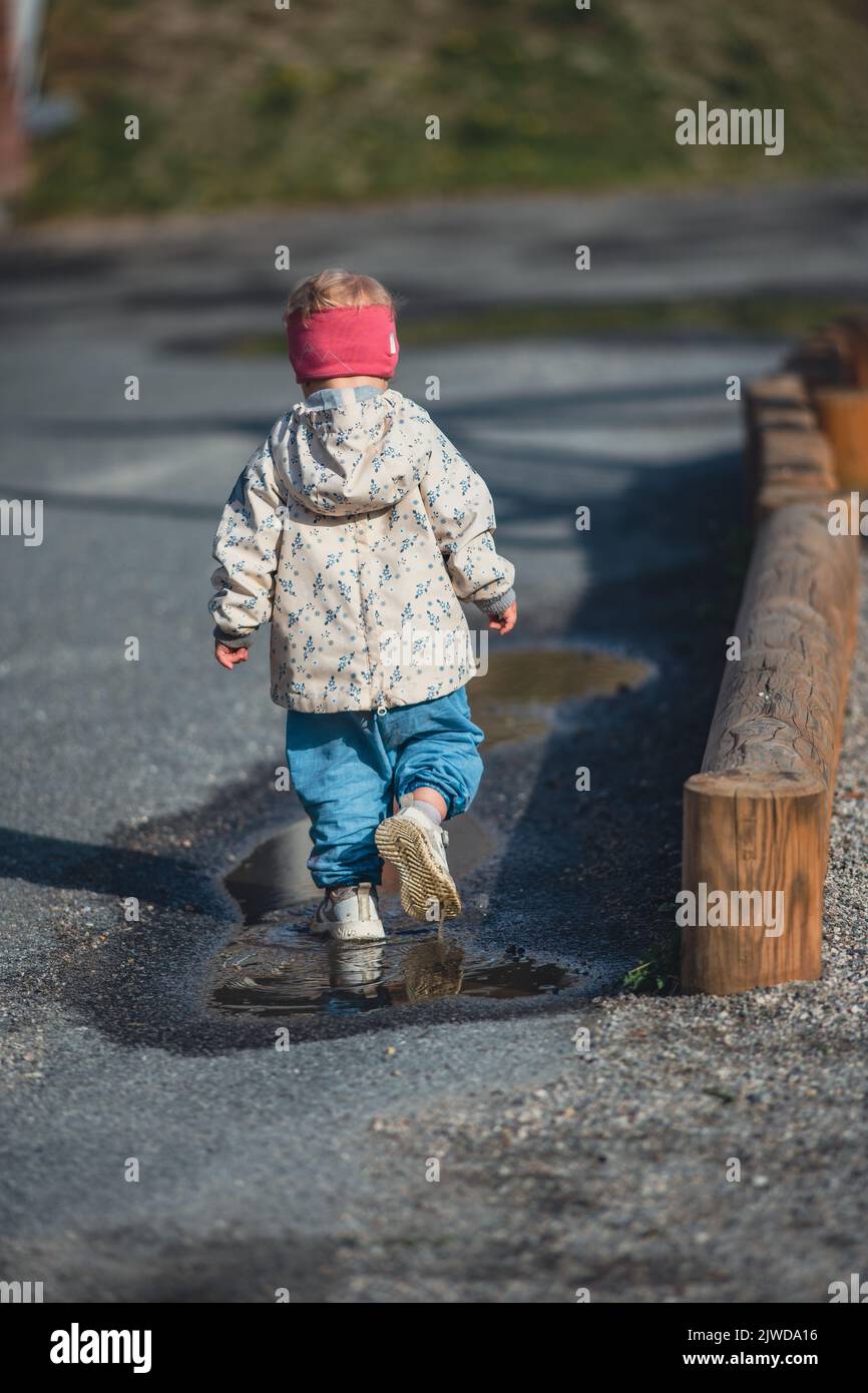 A kid playfully jumping into the puddle Stock Photo - Alamy