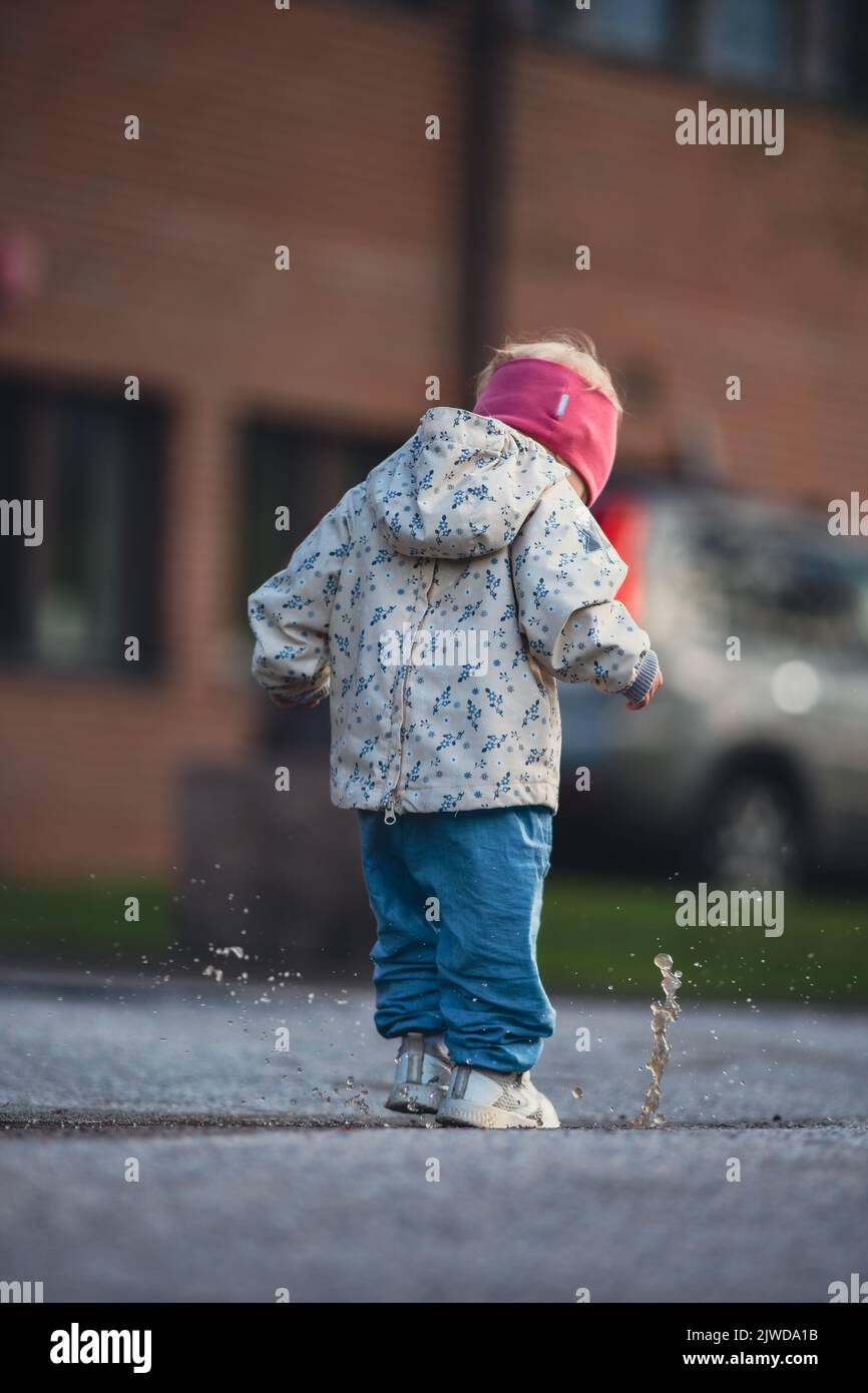 A kid playfully jumping into the puddle Stock Photo - Alamy