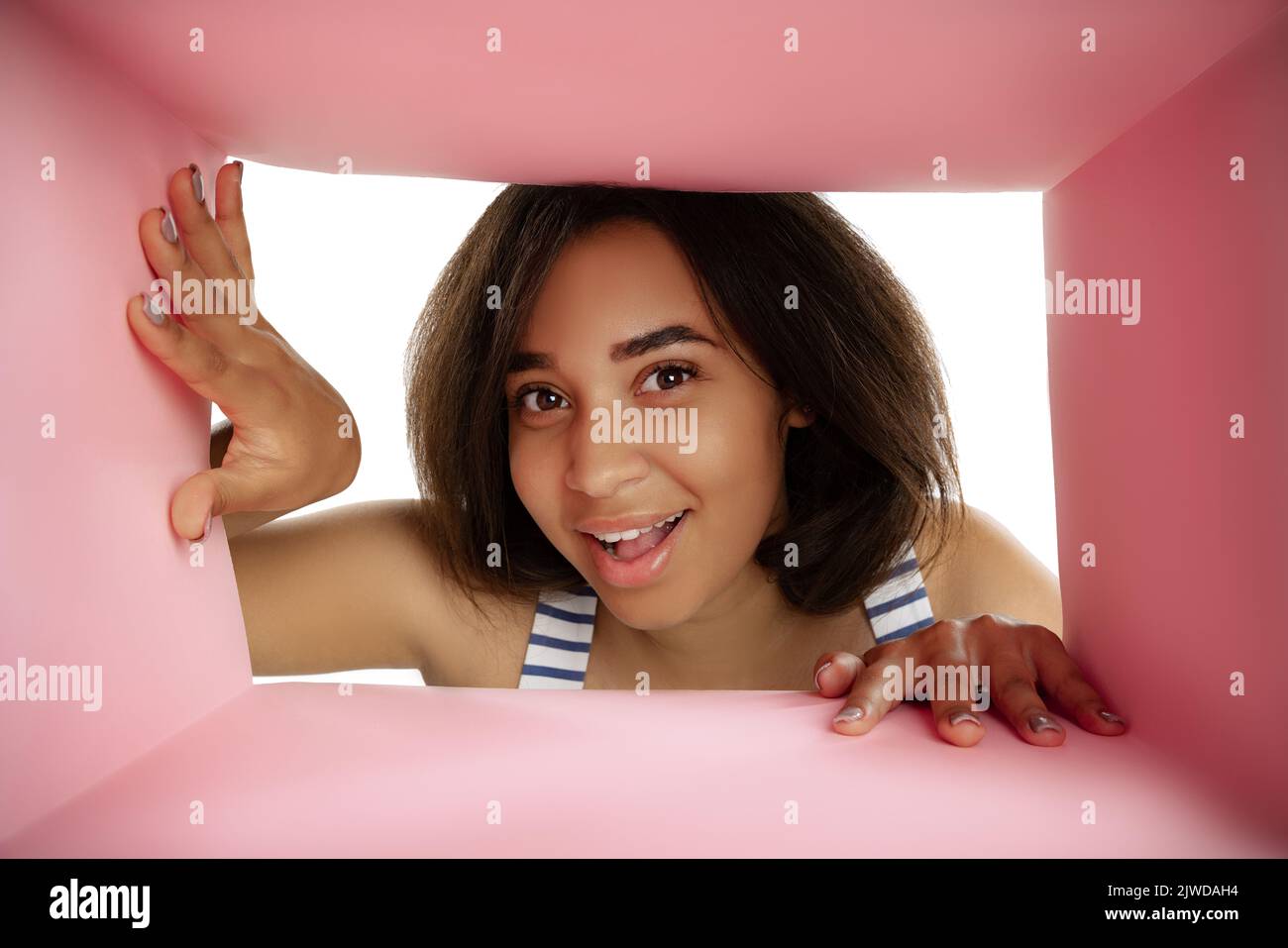 Smiling girl unpacking, opening carton box and looking inside. Package ...