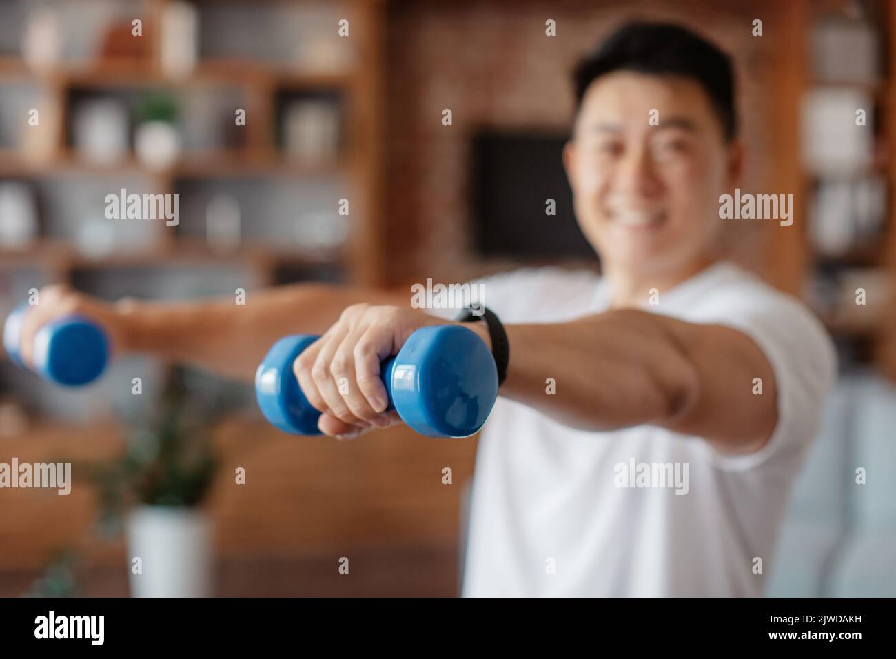 Athlete asian man doing hands exercise with dumbbells in living room ...