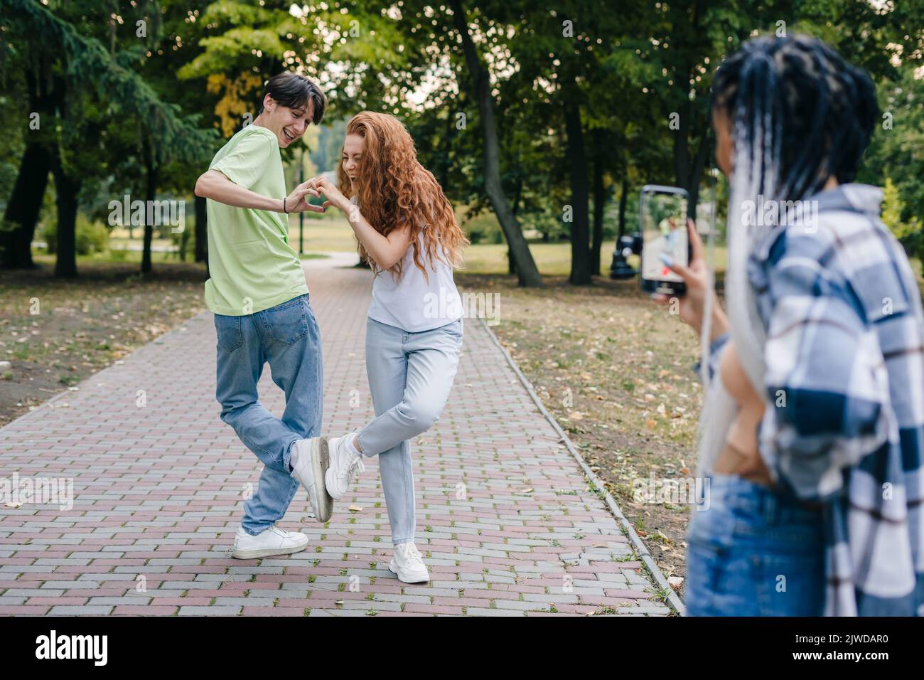 Cheerful beautiful girl standing in the park with a camera and smiling ...