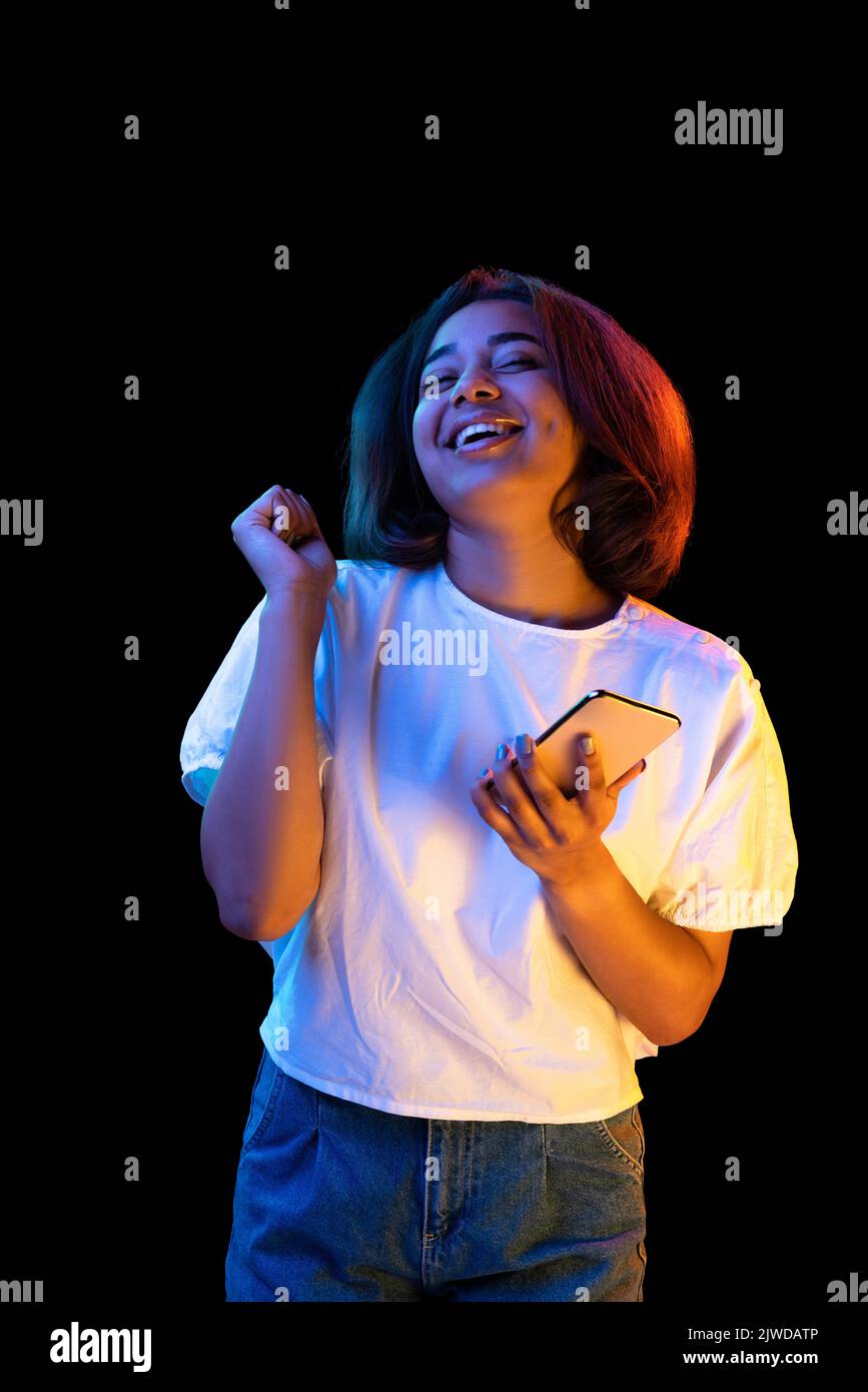 One astonished glad woman in white t-shirt using smart phone with ...