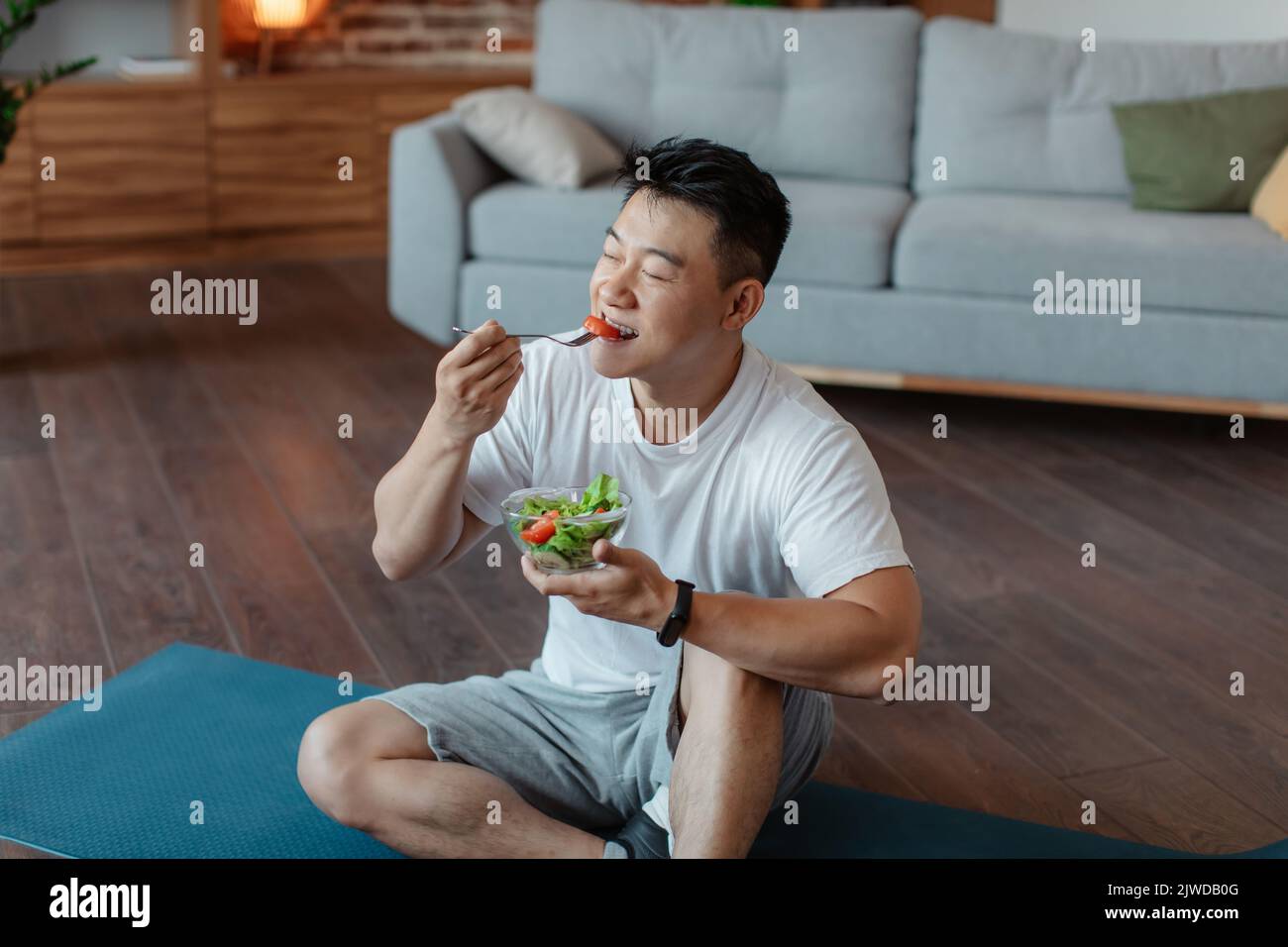 Healthy lifestyle concept. Relaxed asian man eating fresh vegetable ...