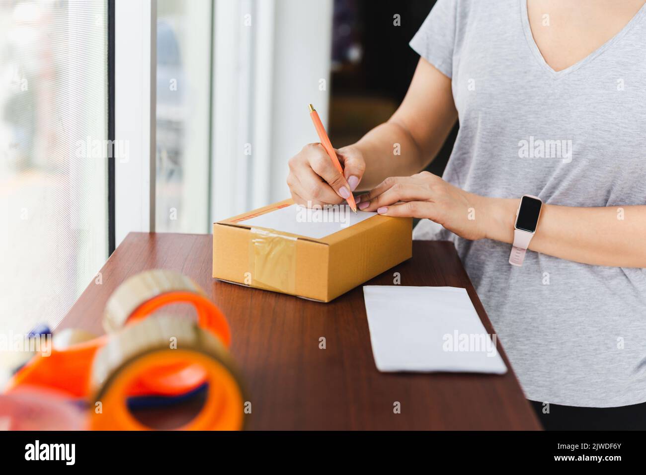 Woman writing address on cardboard box in post office Stock Photo - Alamy