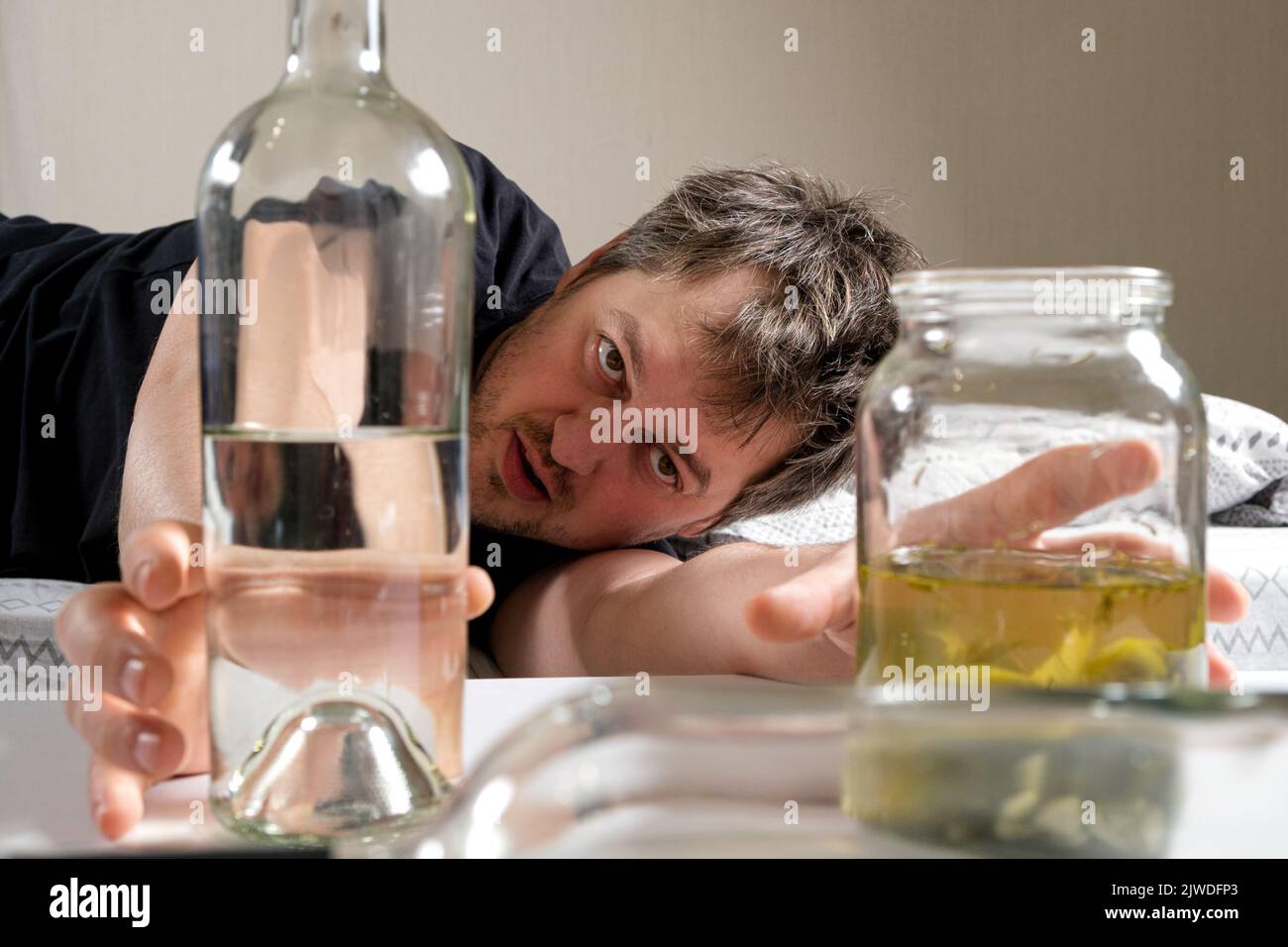 A drunk man with an alcohol addiction takes a bottle of vodka and brine ...