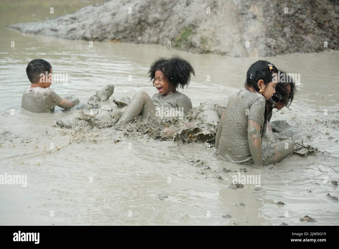 Group of kids playing on muck in the raining day Stock Photo - Alamy