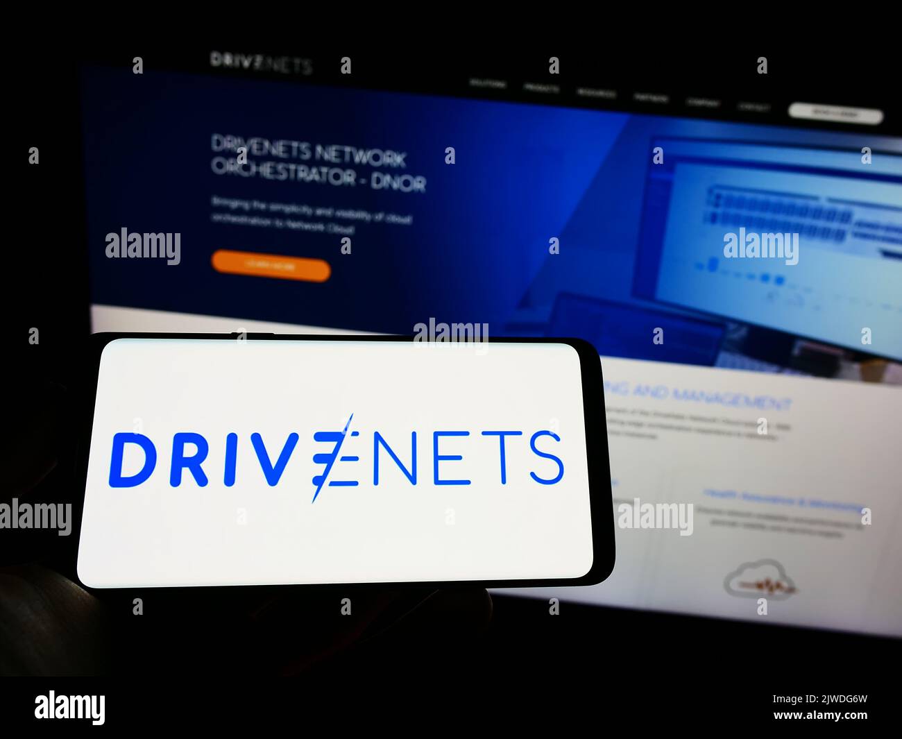 Person holding cellphone with logo of Israeli software company DriveNets Ltd. on screen in front ...