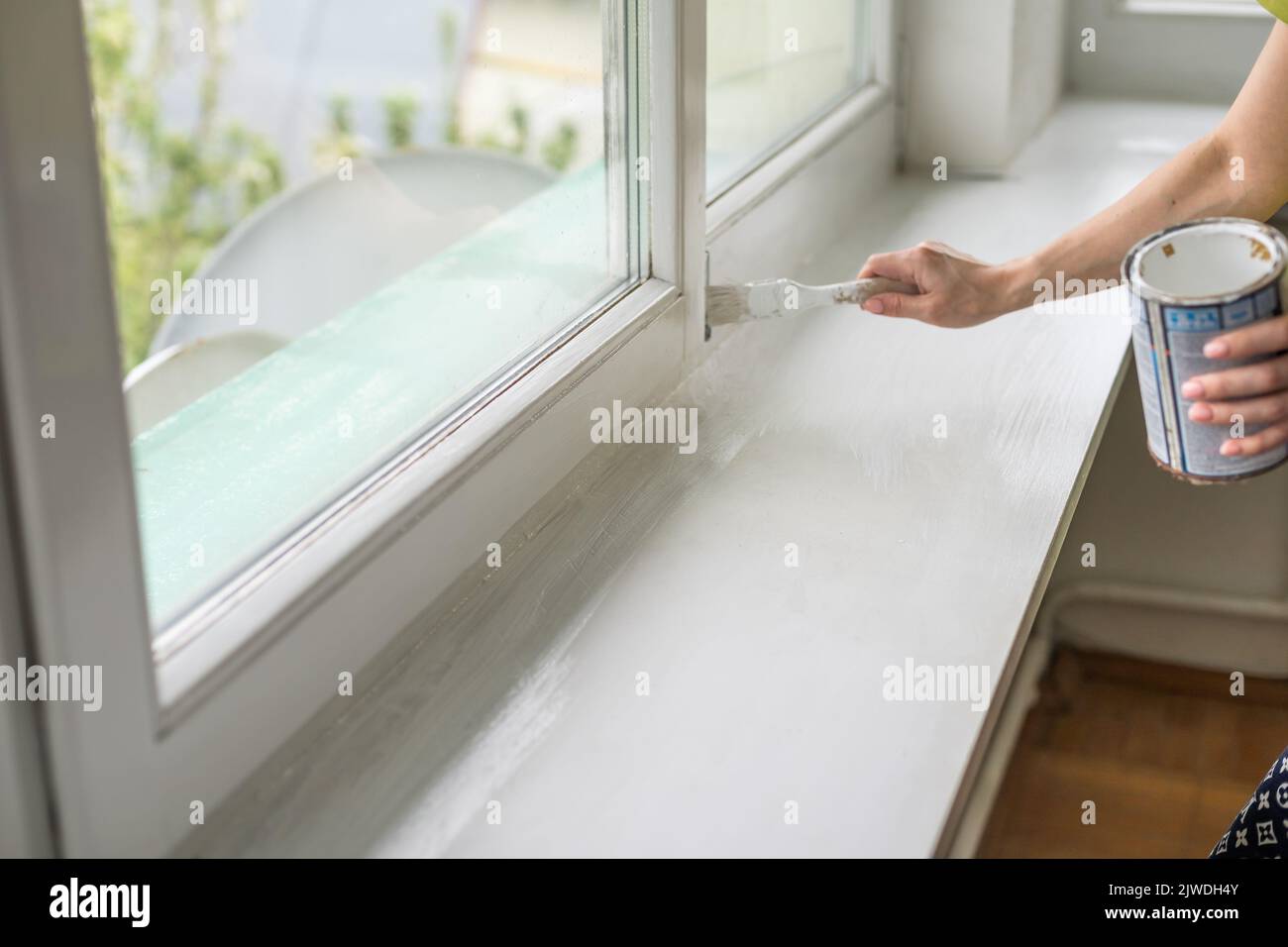 Worker painting frame of old window, painting old windows in white ...