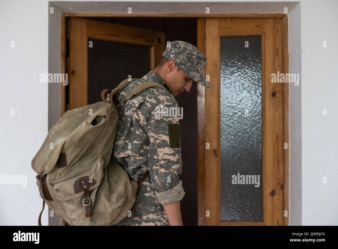 military man with a backpack goes out the door Stock Photo - Alamy