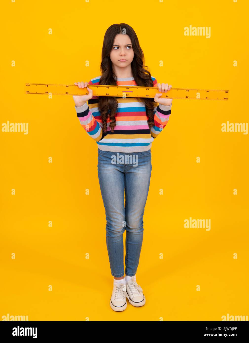 Back to school. School girl hold ruler measuring isolated on yellow ...