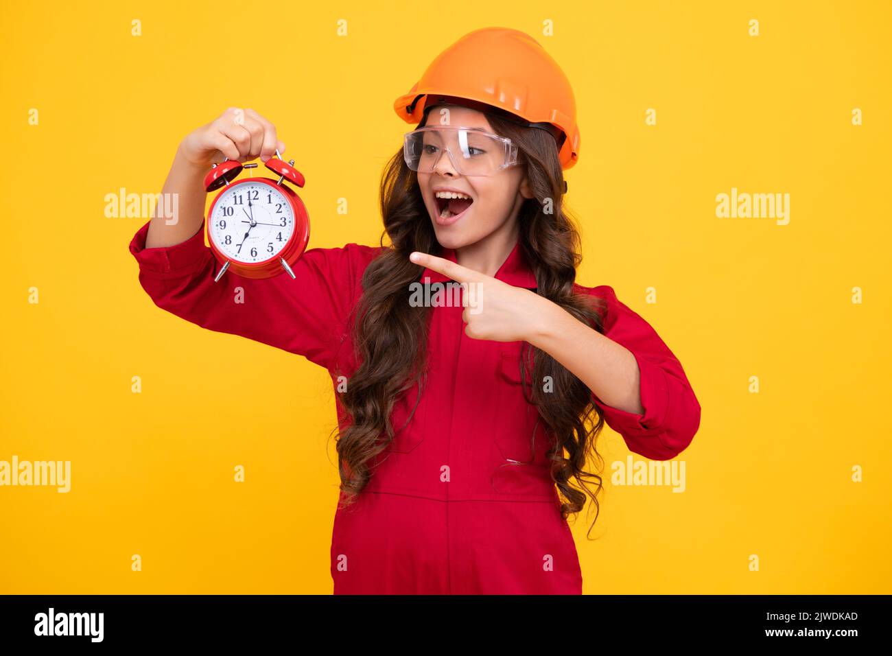 Excited teenager girl in builder helmet and clock alarm. Time to ...