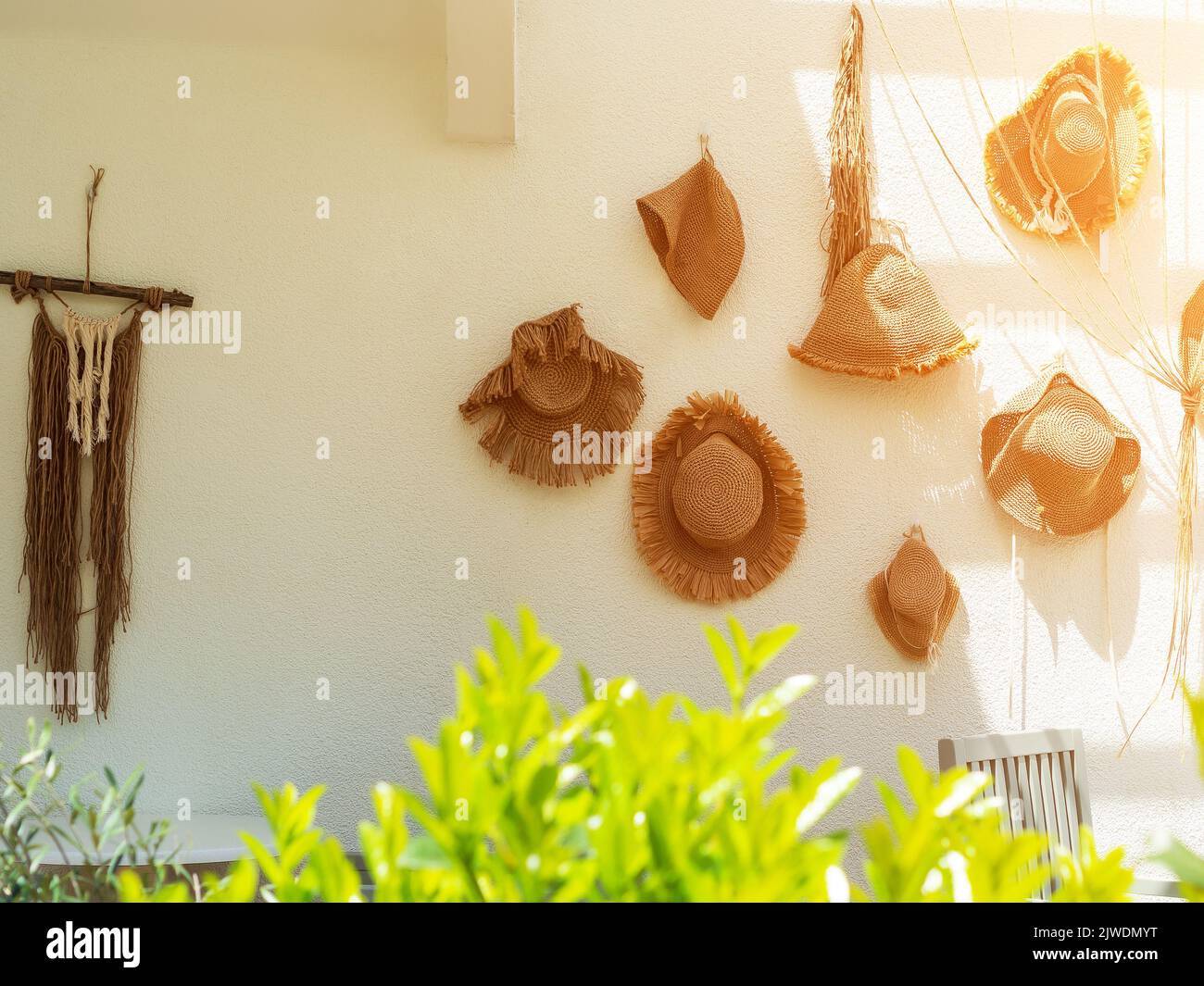 Wicker hats hanging on the wall as decor Stock Photo - Alamy