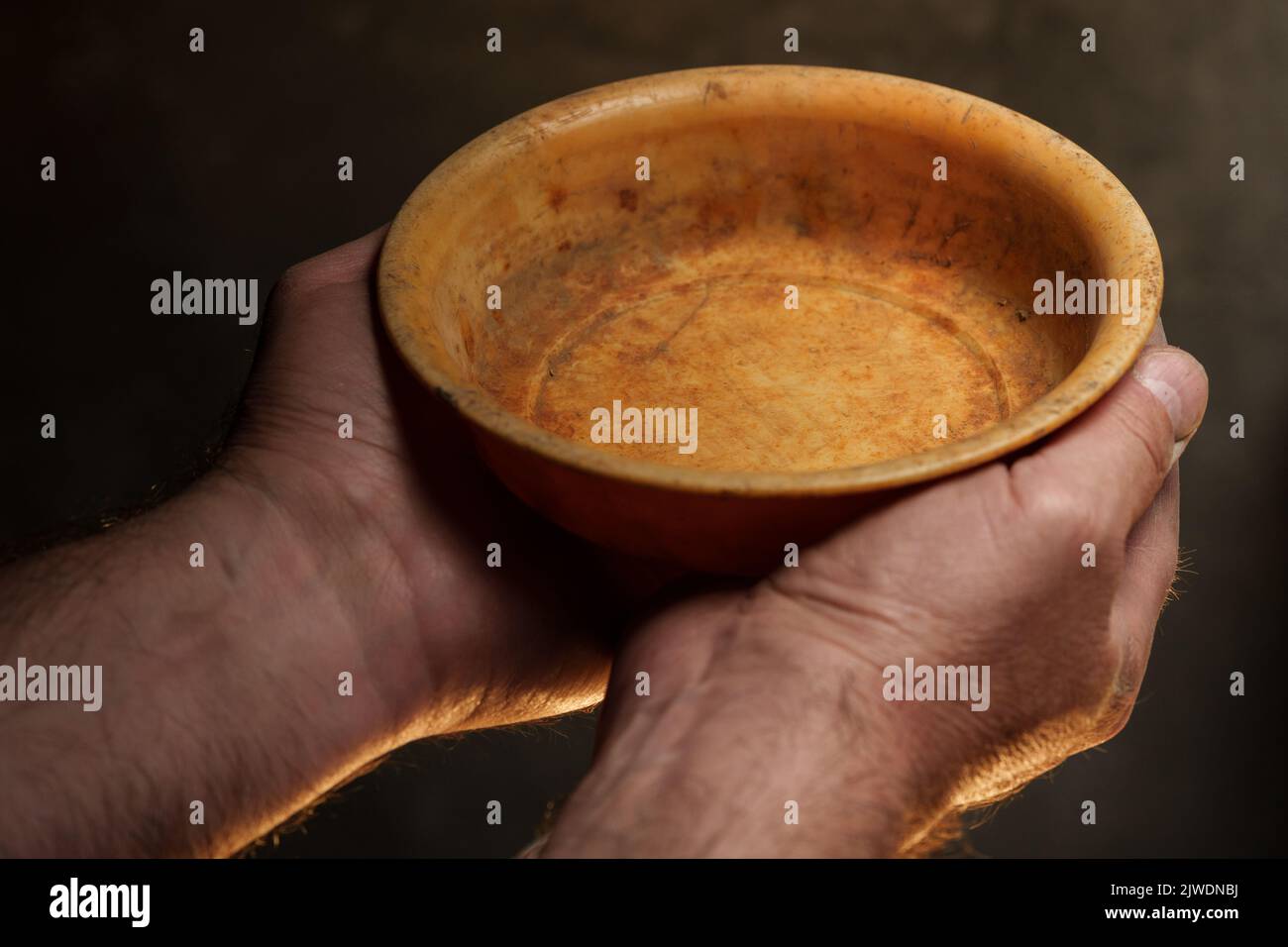 Male hands holding empty plate on dark background, lack of food, hunger ...