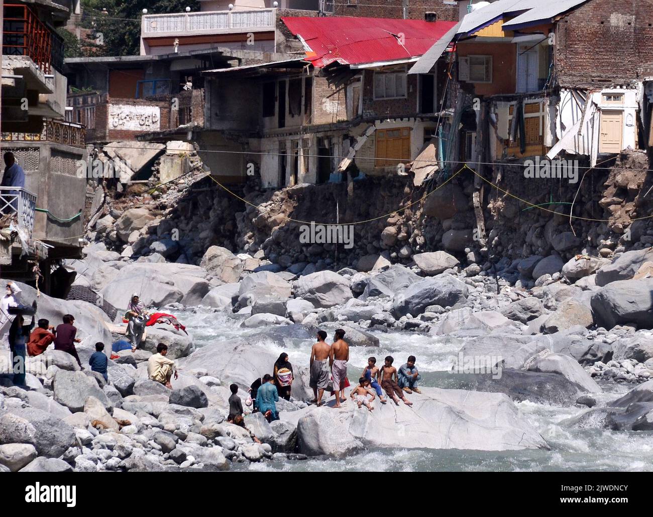 Swat. 5th Sep, 2022. Flood-affected people are seen in front of damaged ...