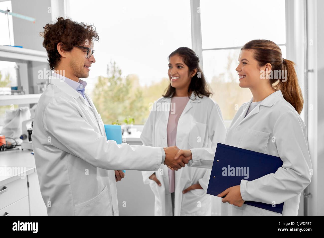 scientists shaking hands in laboratory Stock Photo - Alamy
