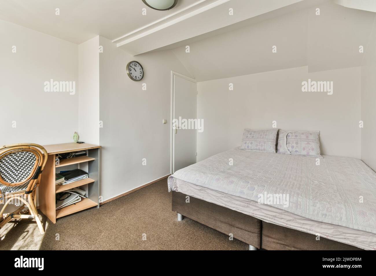 Comfortable bed covered with checkered blanket and located in light ...