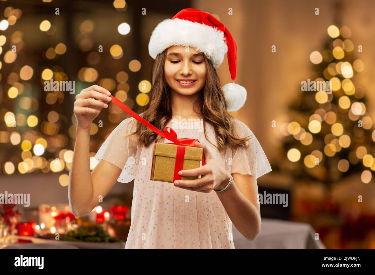 smiling girl in santa hat opening christmas gift Stock Photo - Alamy