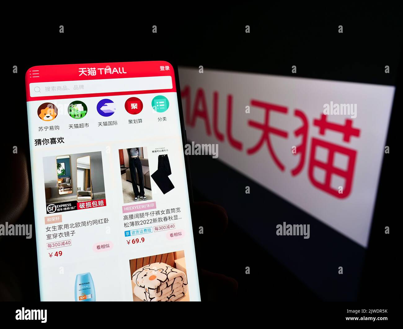 Person holding smartphone with website of Chinese e-commerce company Tmall.com (Tmall) on screen ...