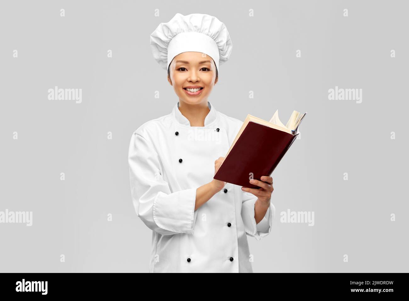 smiling female chef reading cook book Stock Photo - Alamy