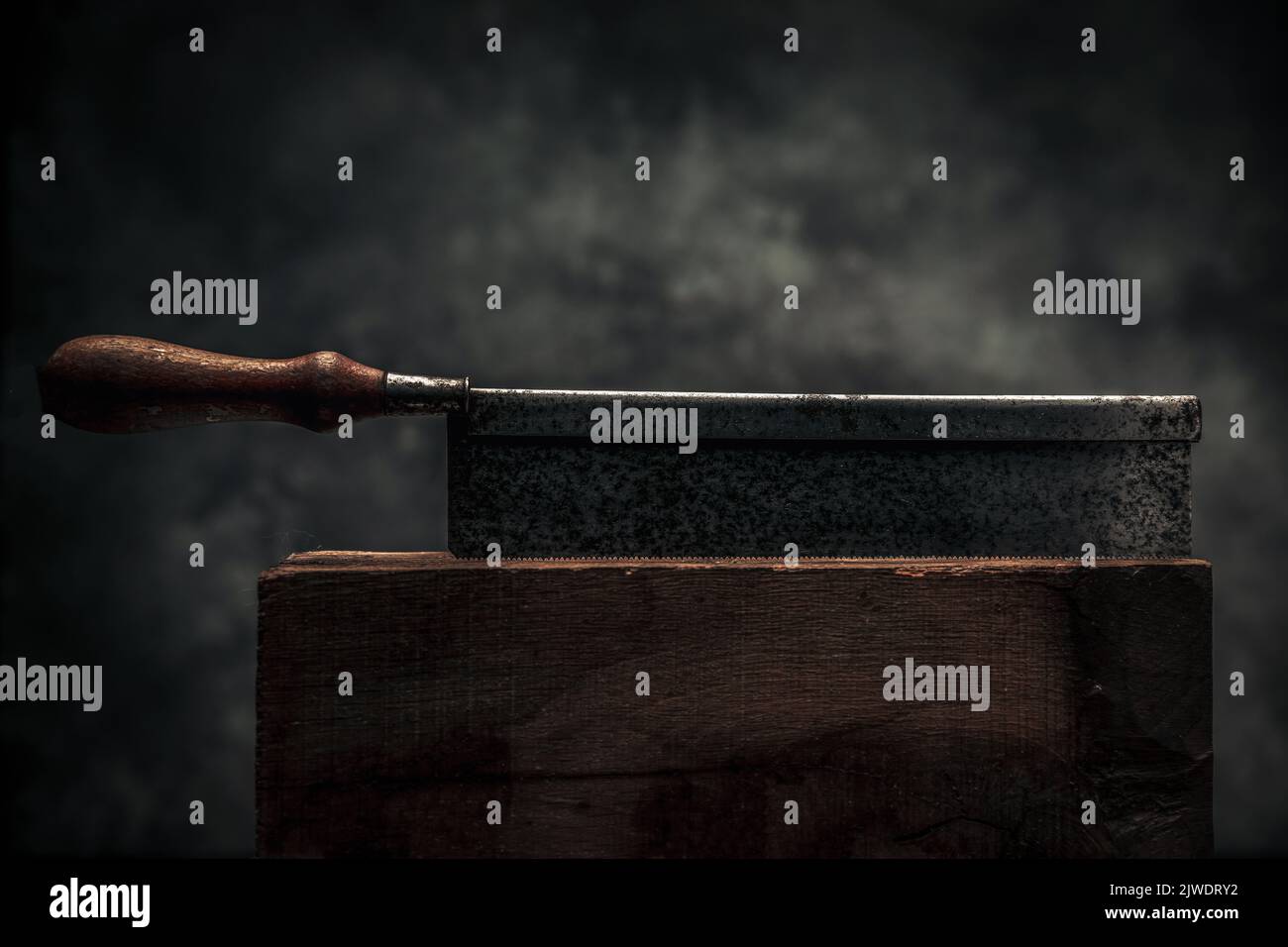 old rusty handsaw with serrated blade in top of wooden workbench in ...