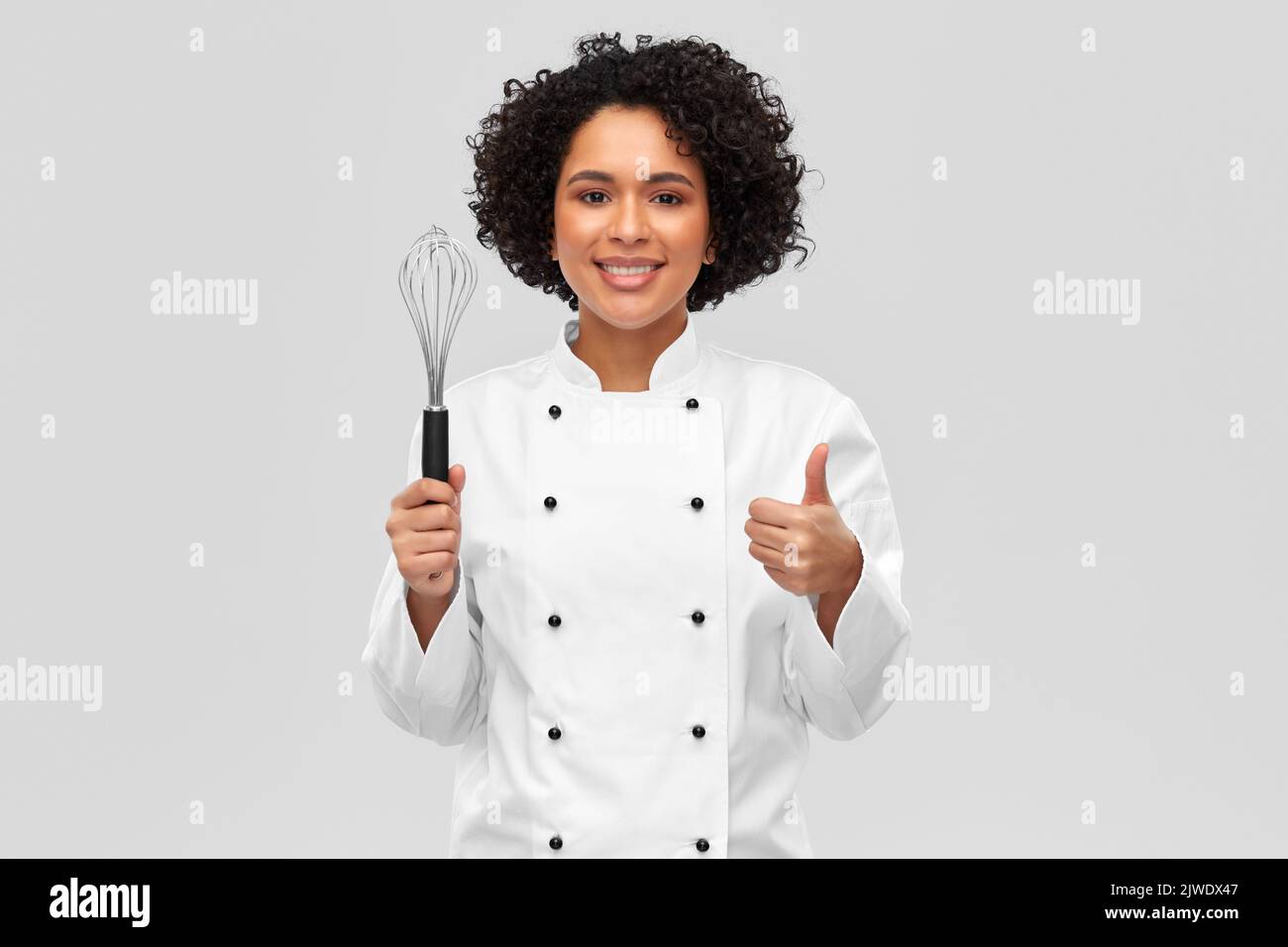 smiling female chef with whisk showing thumbs up Stock Photo - Alamy